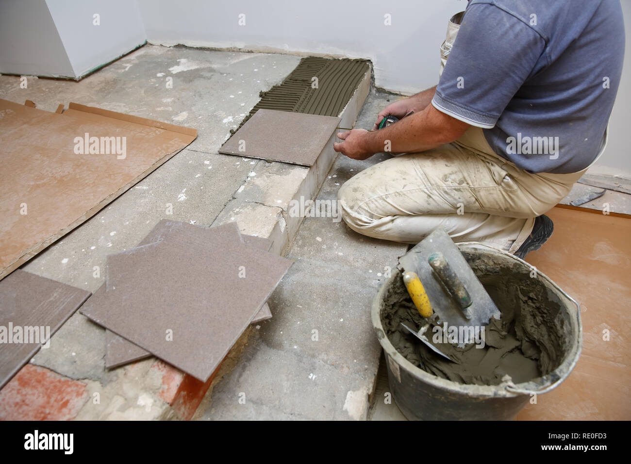 The builder arranges ceramic tiles on the stairs inside the building ...