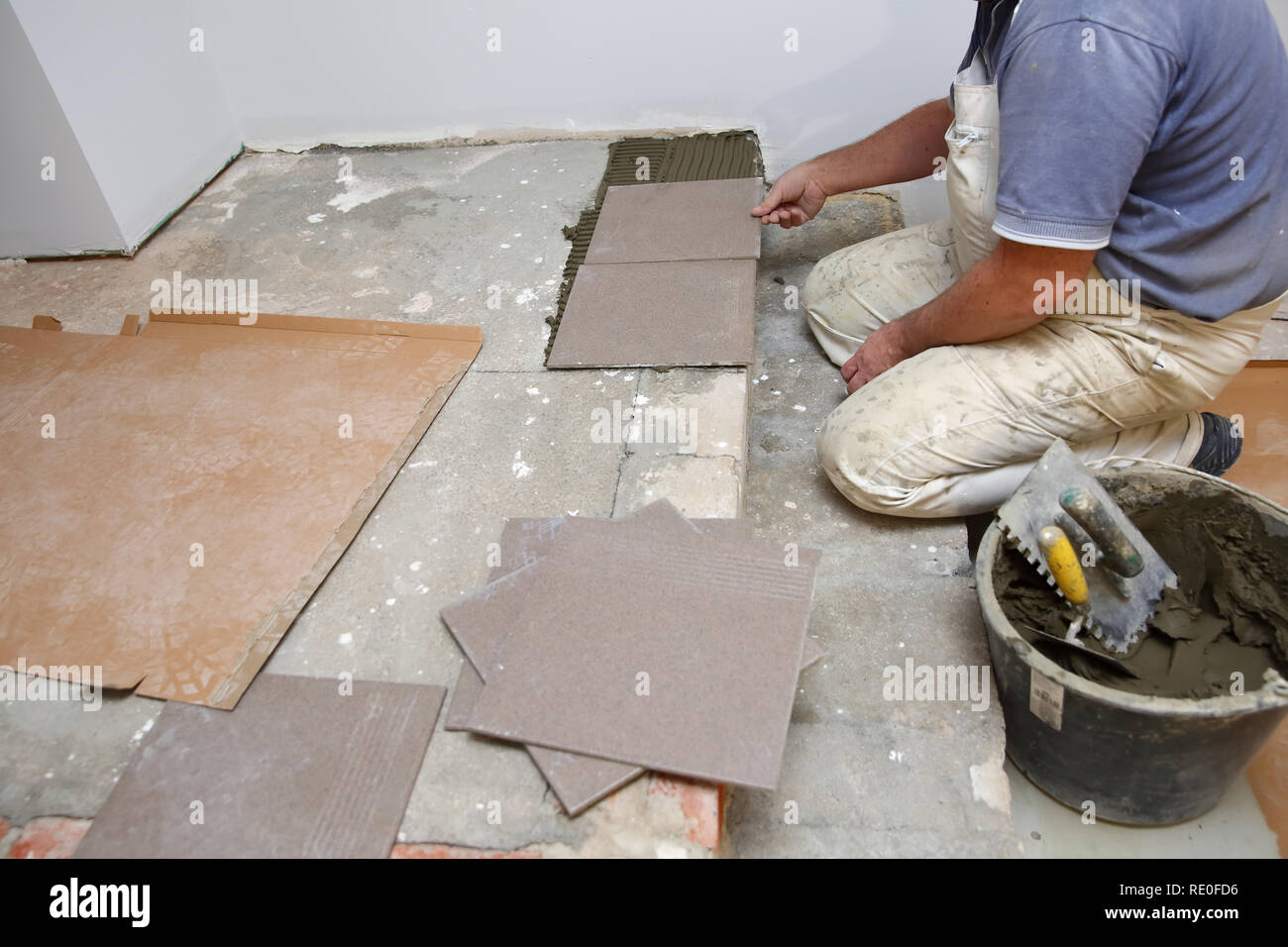 The builder arranges ceramic tiles on the stairs inside the building ...