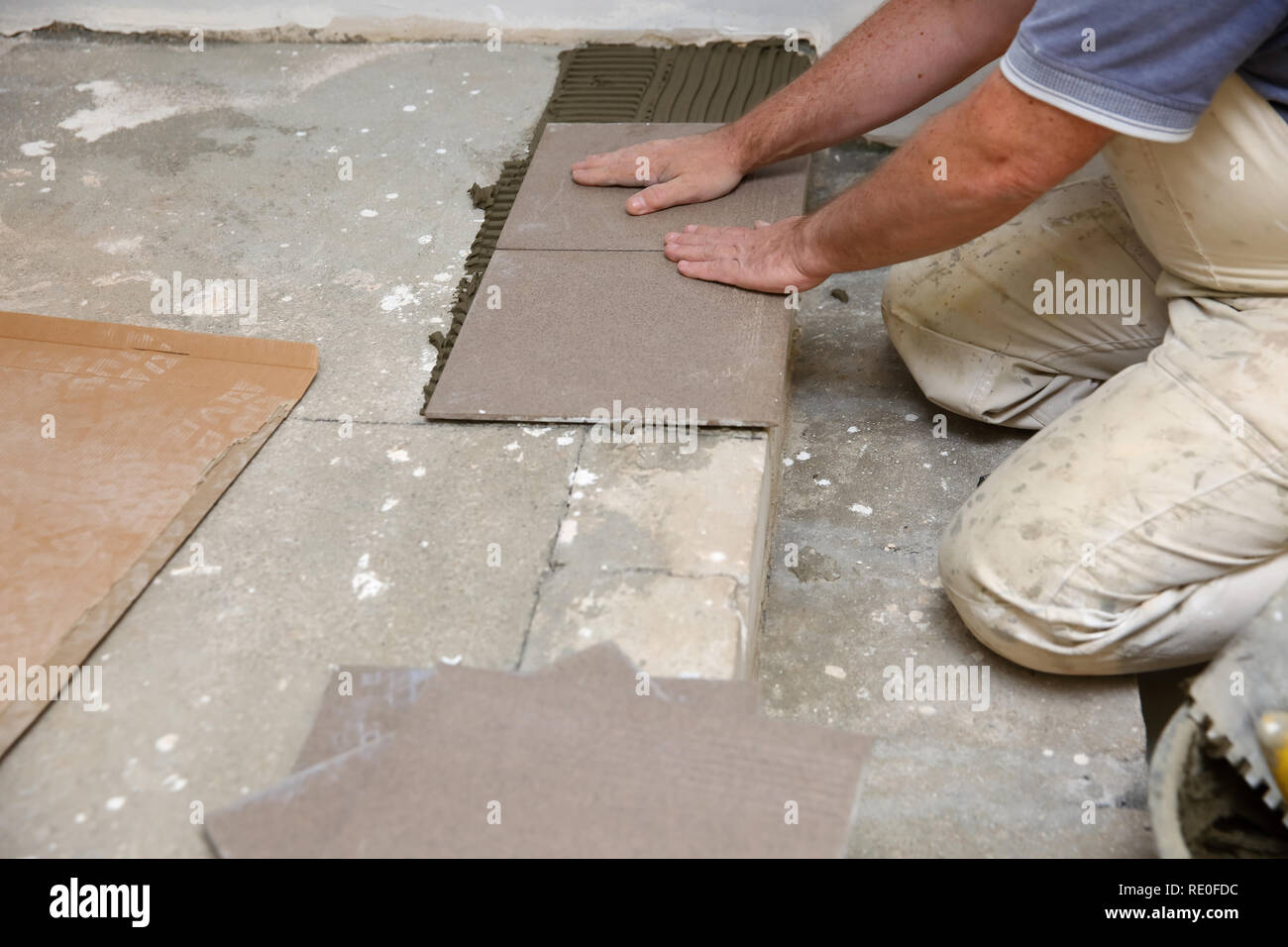 The builder arranges ceramic tiles on the stairs inside the building ...