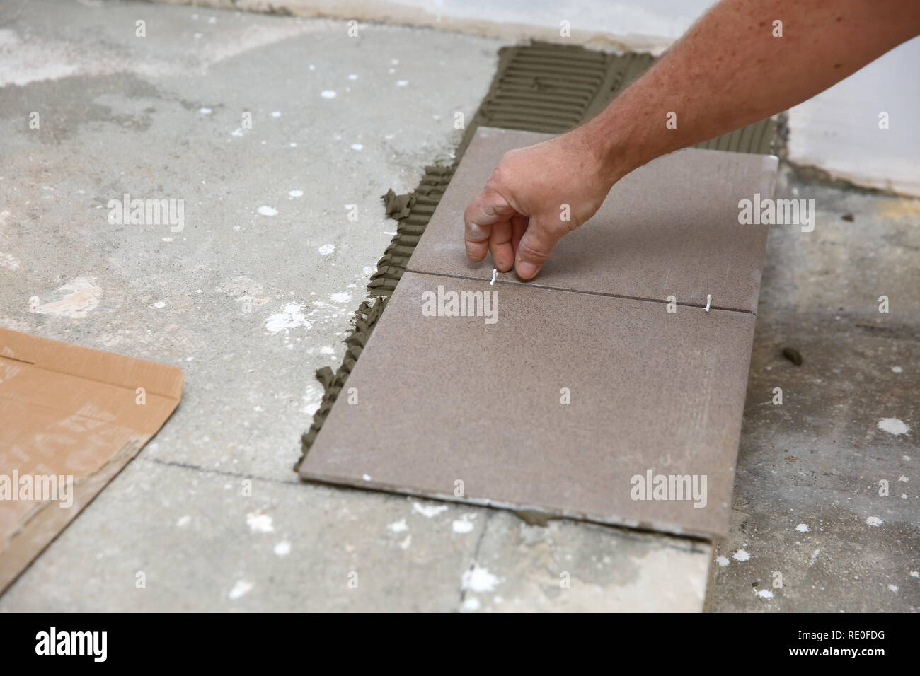 The builder arranges ceramic tiles on the stairs inside the building ...