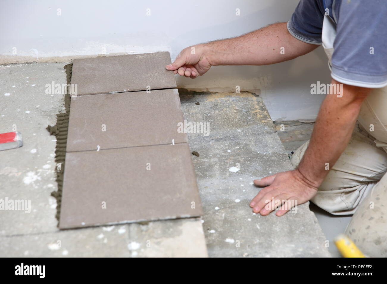 The builder arranges ceramic tiles on the stairs inside the building ...