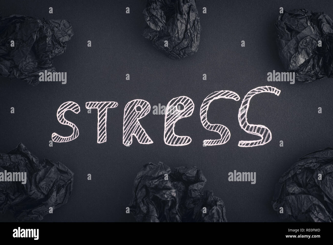 The word Stress on a black background and black crumpled paper balls ...