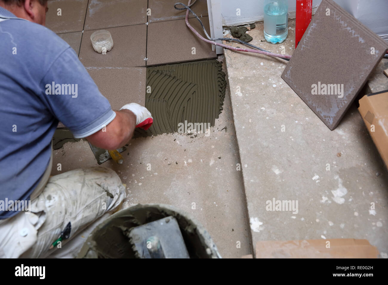 The builder arranges ceramic tiles on the stairs inside the building ...