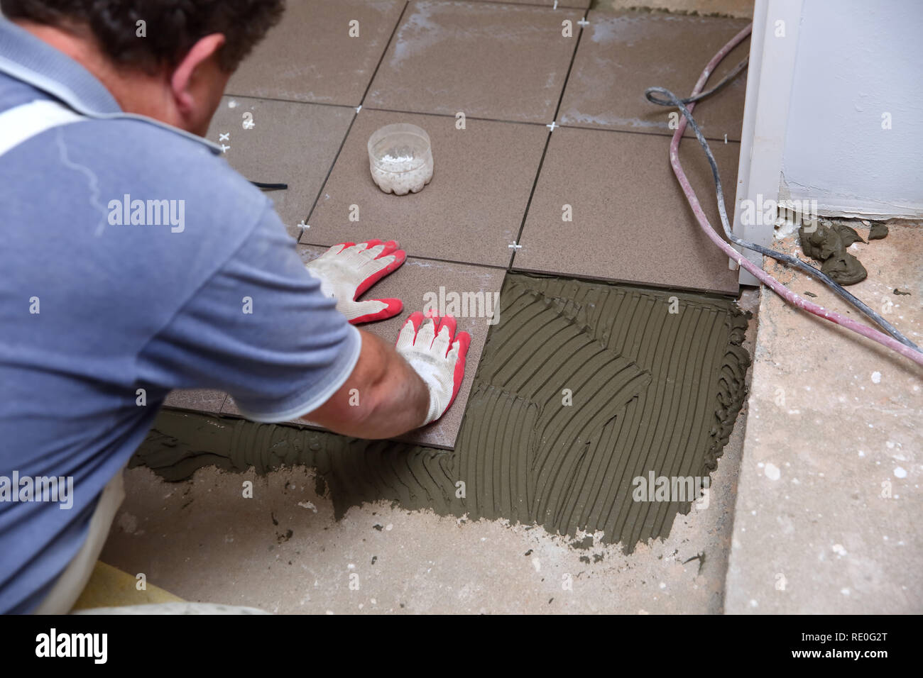 The builder arranges ceramic tiles on the stairs inside the building ...