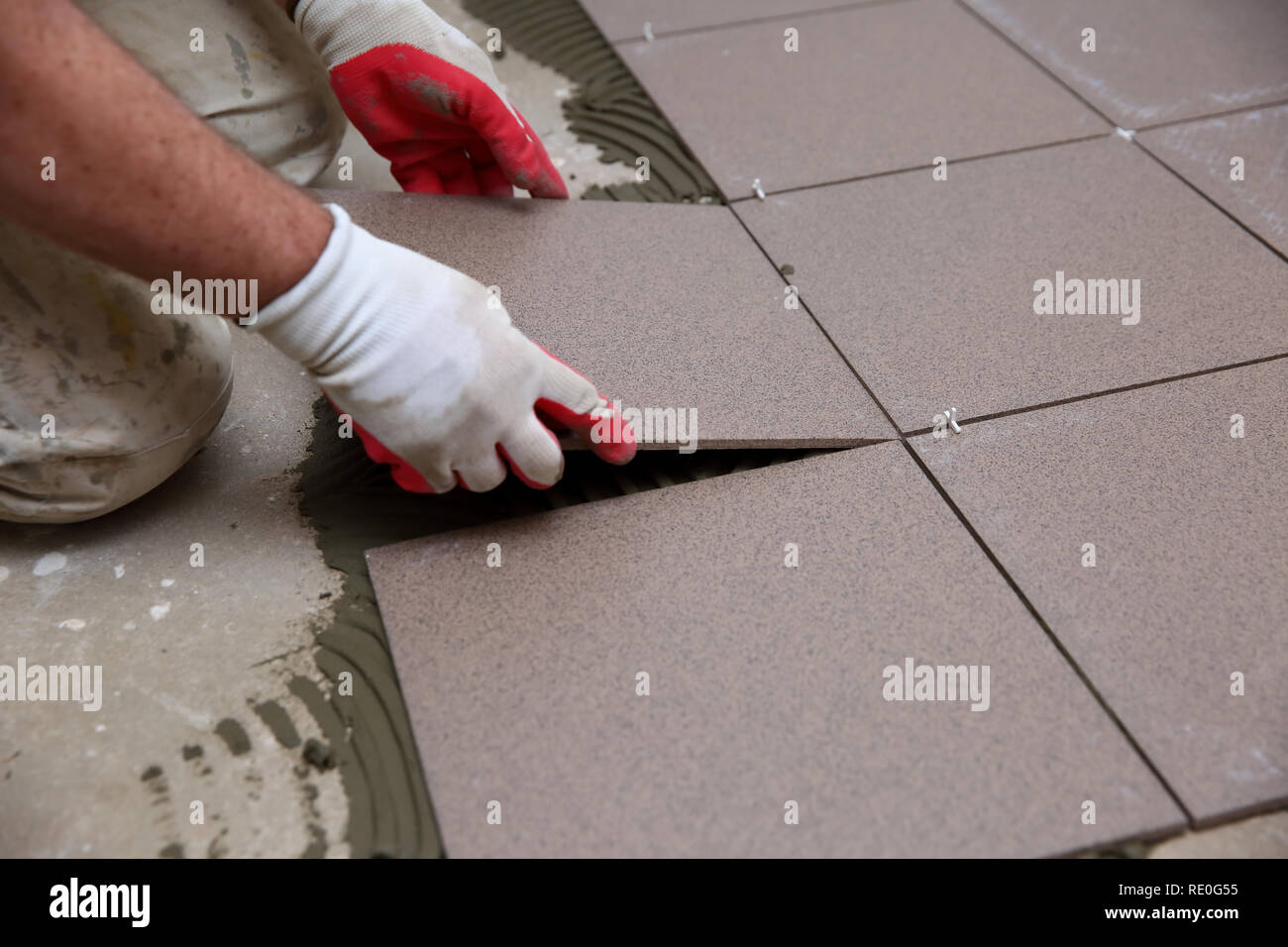 The builder arranges ceramic tiles on the stairs inside the building ...