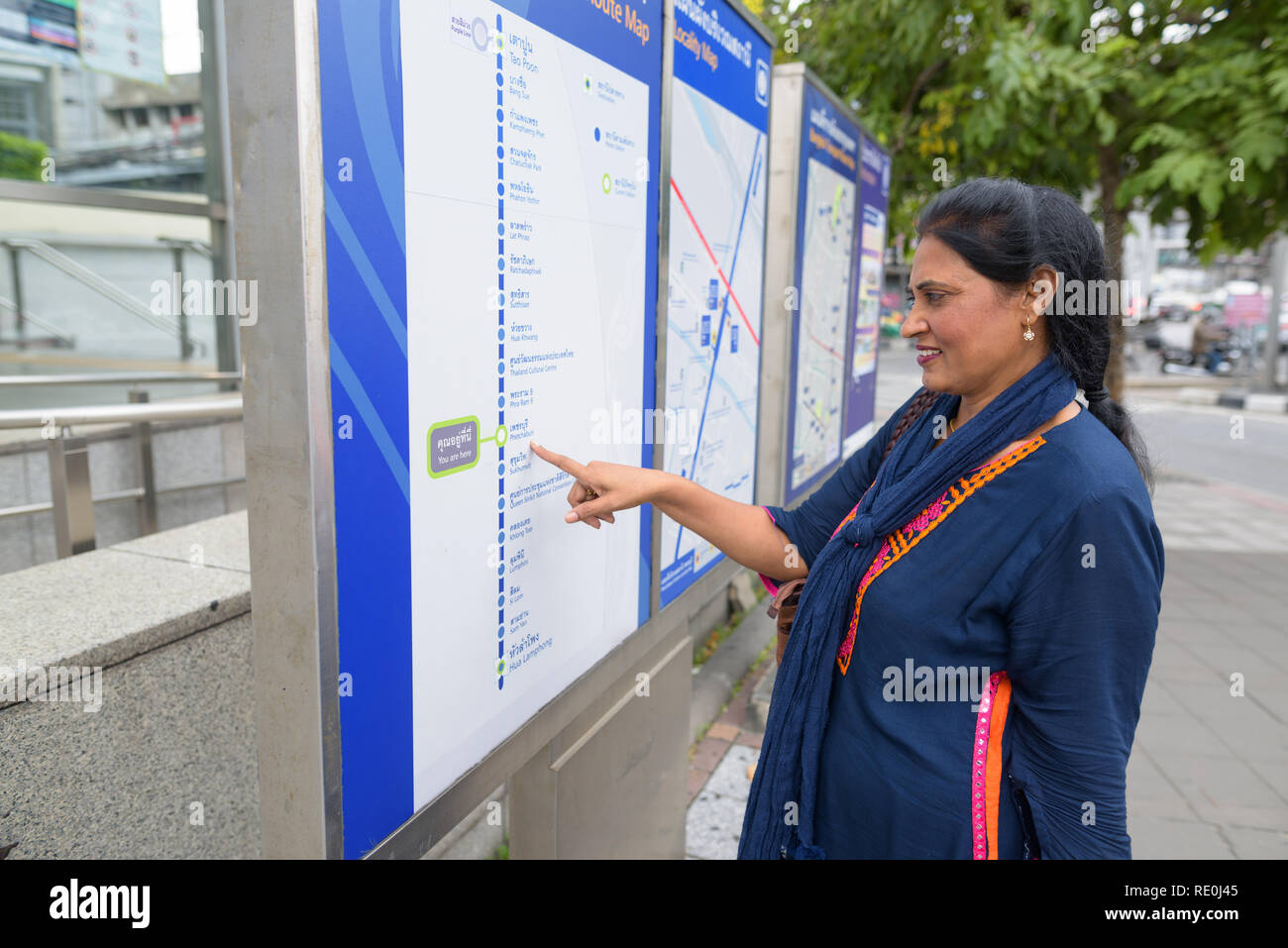 Mature beautiful Indian woman looking at train map outdoors Stock Photo ...