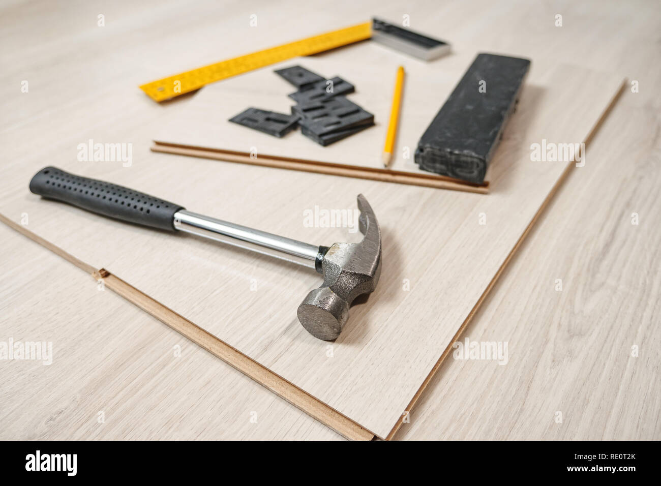 Closeup of wooden plank with hammer and instruments for floor layering ...