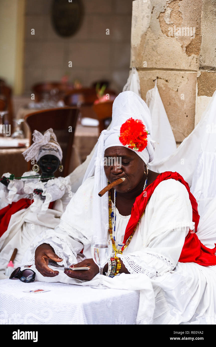 Dark-skinned Cuban in white costume tells fortunes to tourists in ...