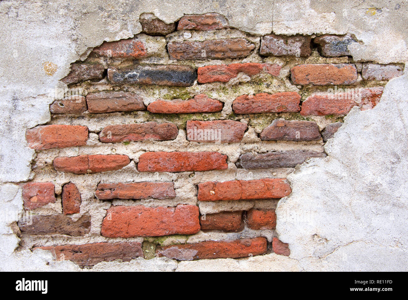Old brick wall covered in concrete, weather worn concrete layer has ...