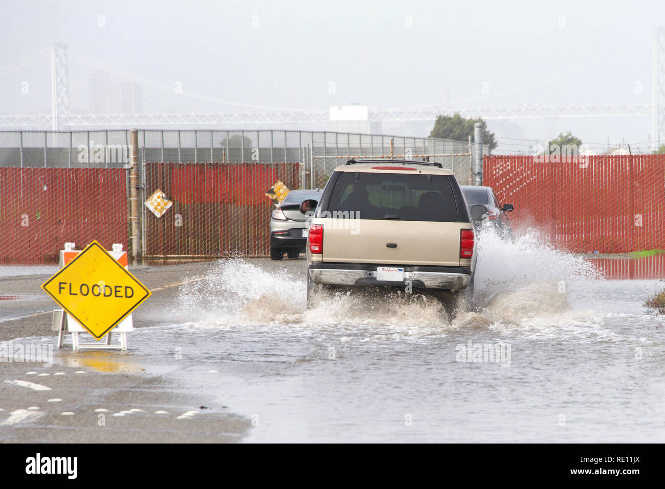 Car driving through flooded area on road with warning sign clearly ...