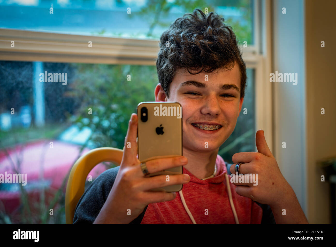 Teenage boy with his new iPhone x, smiling and giving thumbs up Stock ...