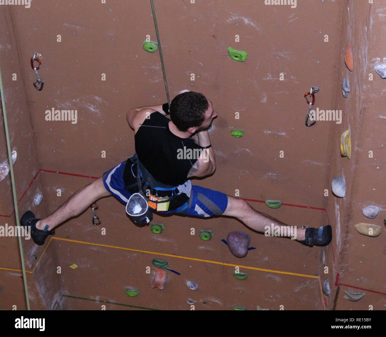 Climber holding splits while climbing brown wall Stock Photo - Alamy