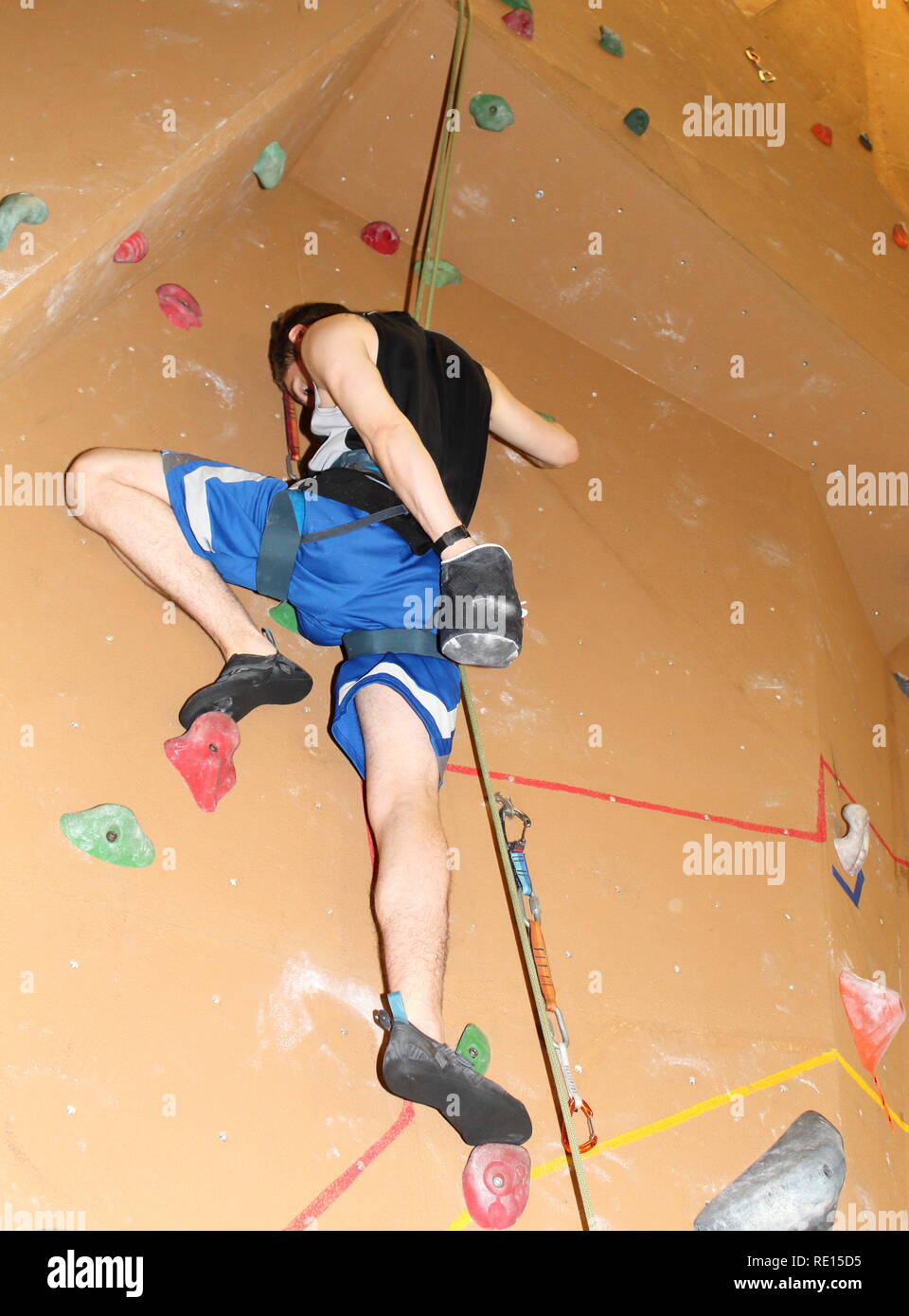 Climber chalking up while ascending brown wall Stock Photo - Alamy