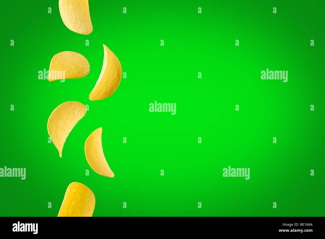 Falling potato chips isolated on green background. Flying crispy snacks ...