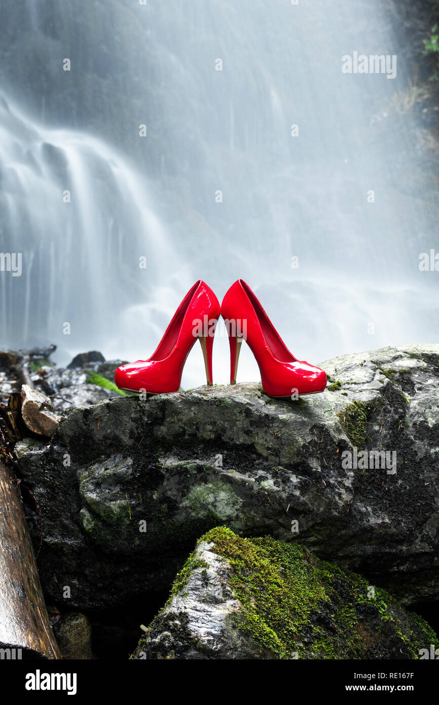 red women's shoes in front of a waterfall Stock Photo - Alamy