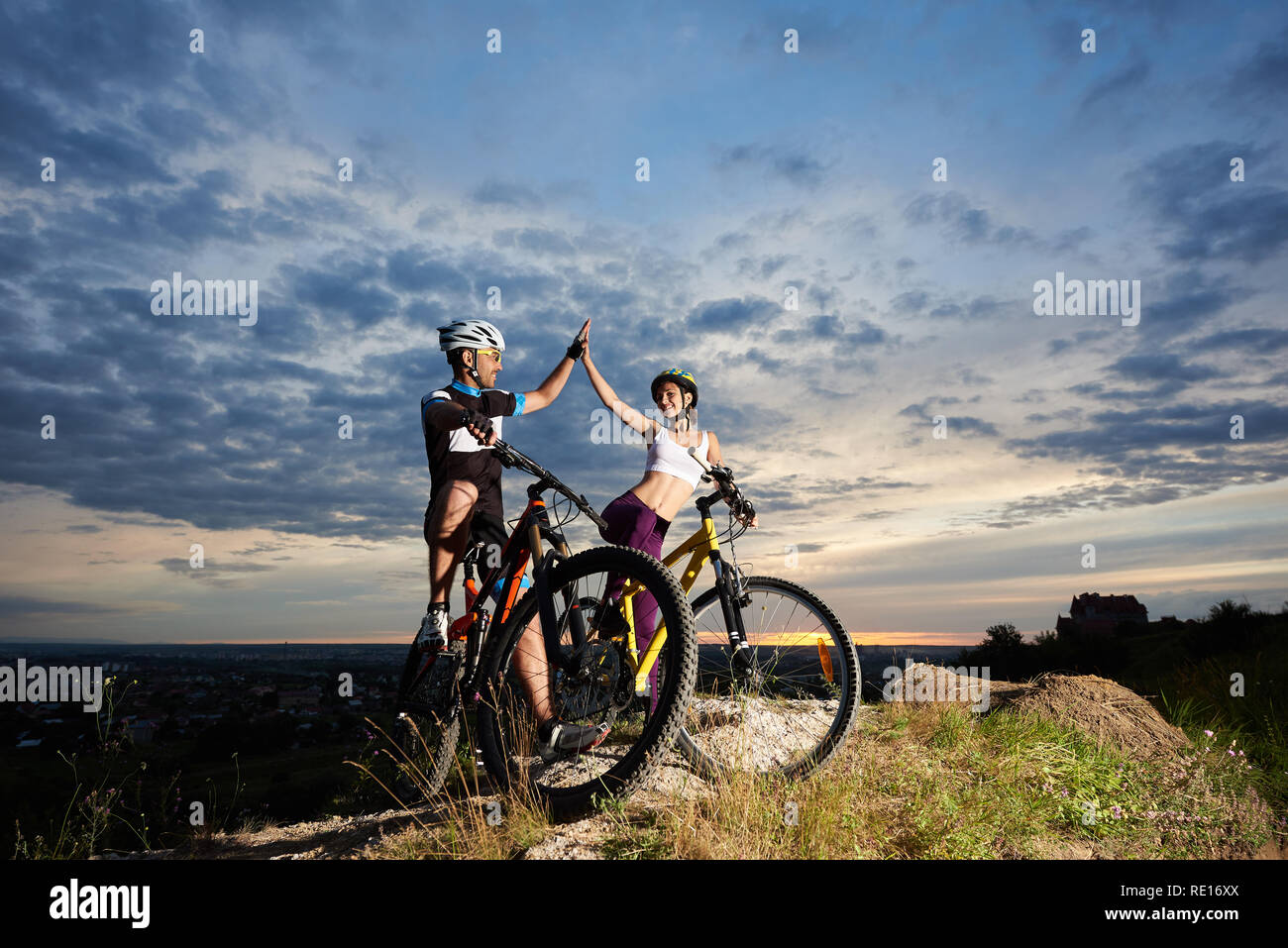 Two cheerful and positive couple of cyclists highing five, smiling and ...