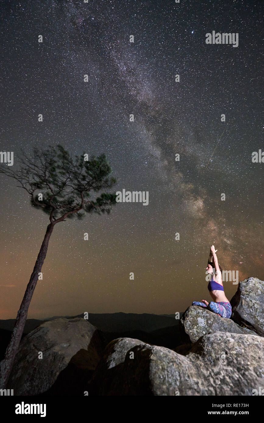 Beautiful summer night in mountains. Woman sitting alone on top of huge ...