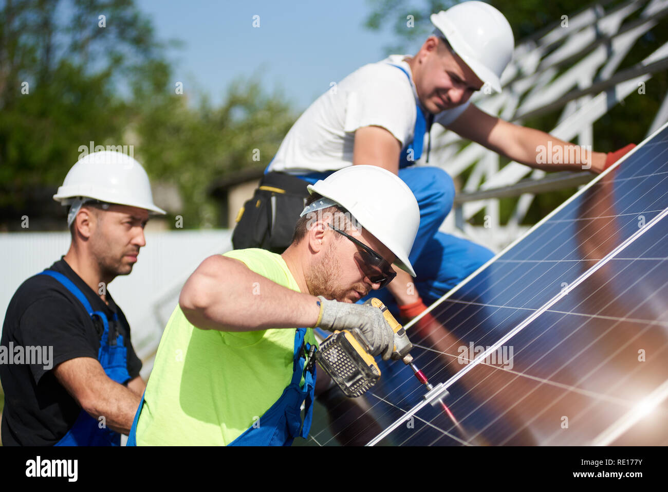 Three professional technicians installing solar photo voltaic panel to ...