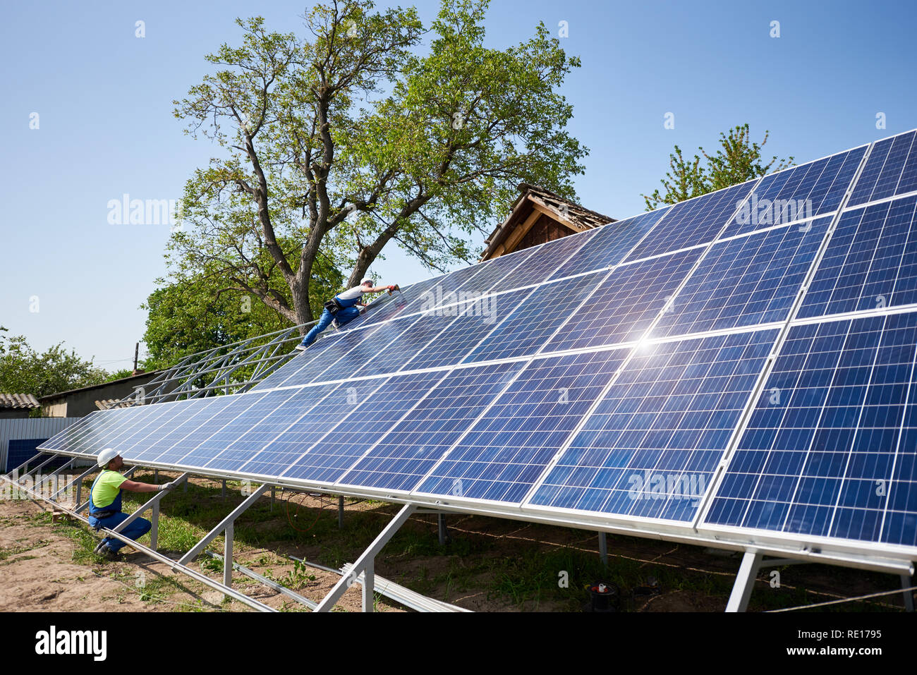 Two technicians working on exterior solar panel photo voltaic system ...
