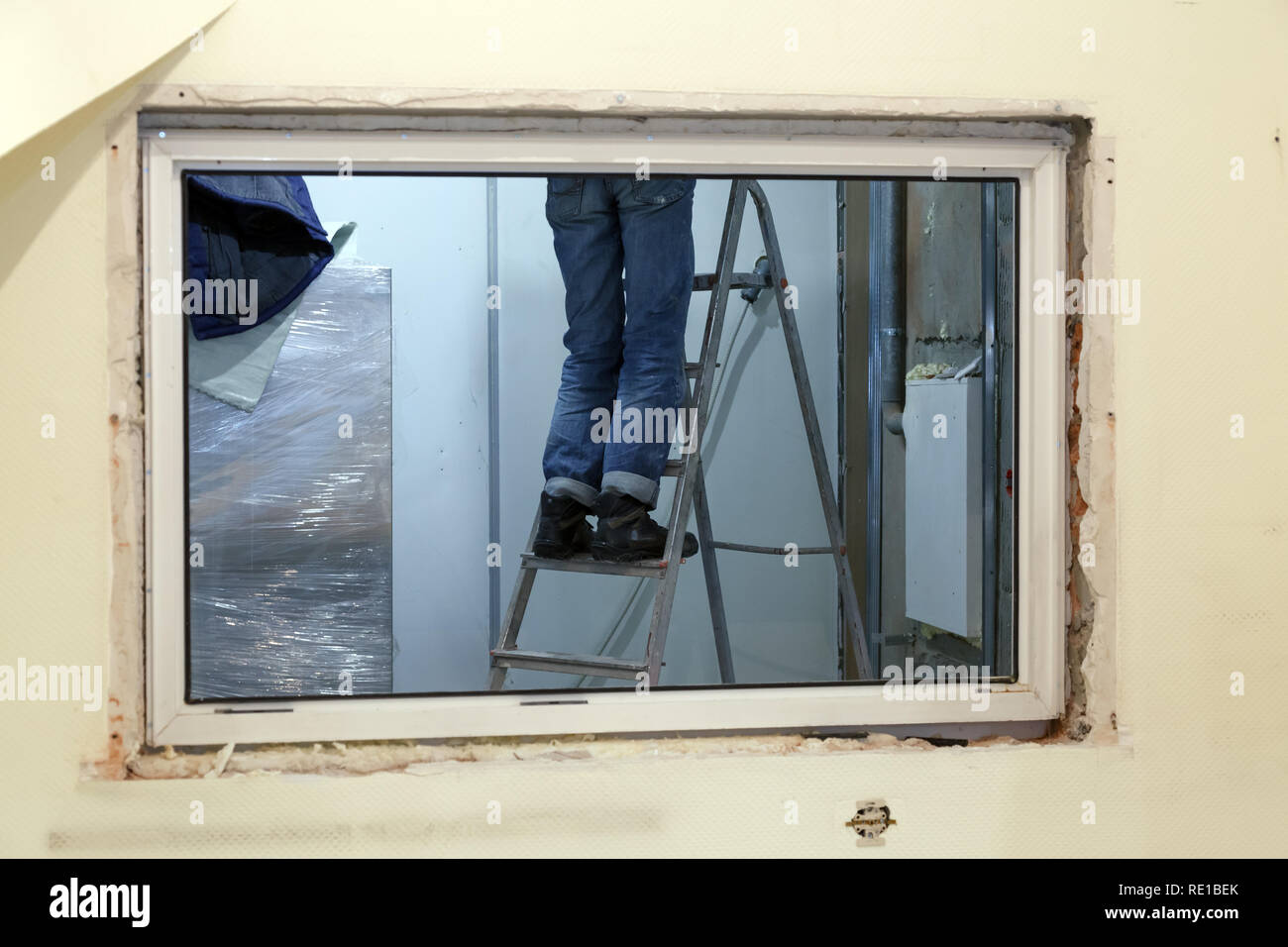 Worker in uniform stands on stepladder in a window opening. Concept ...