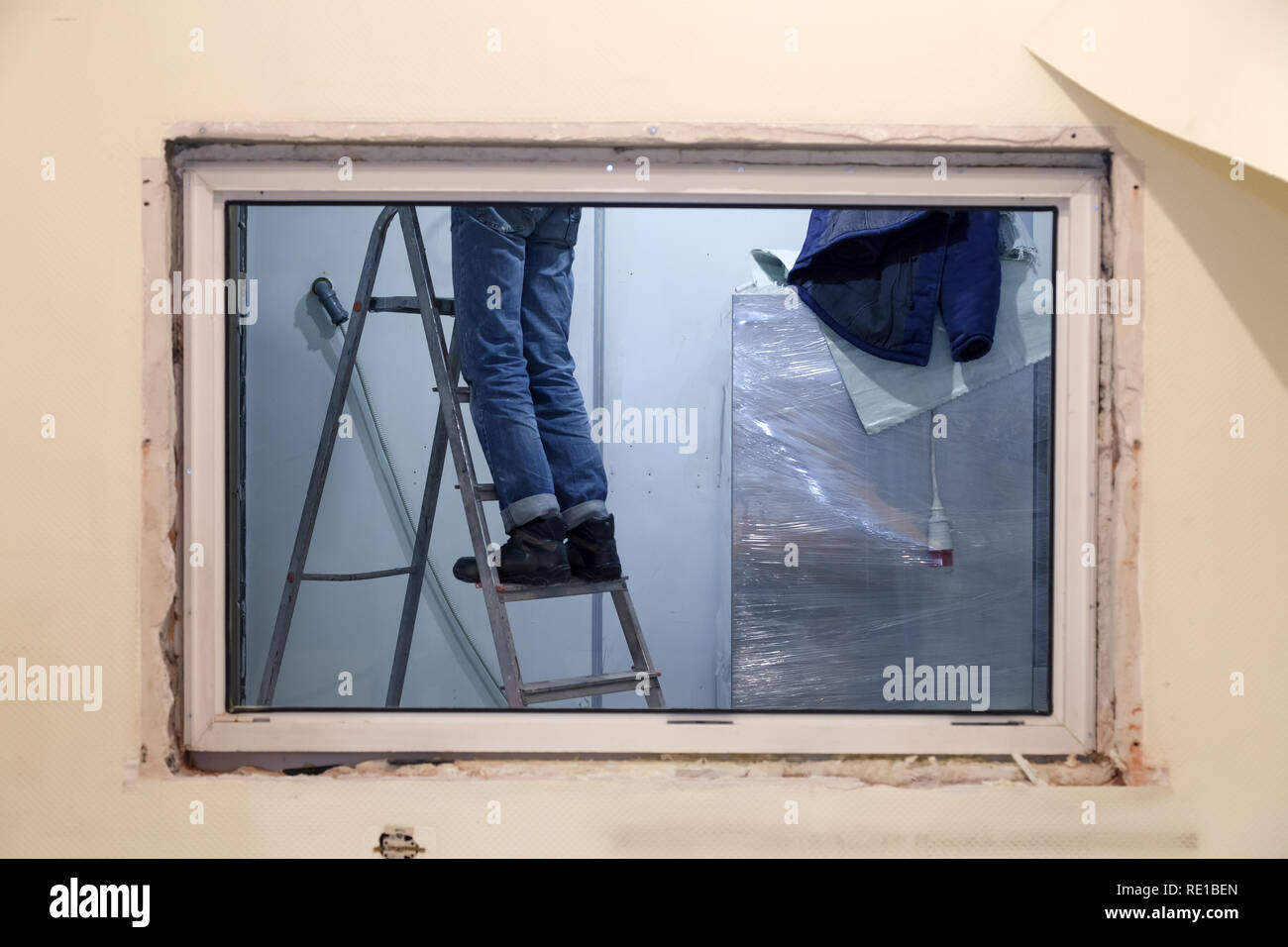 Worker in uniform stands on stepladder in a window opening. Concept ...