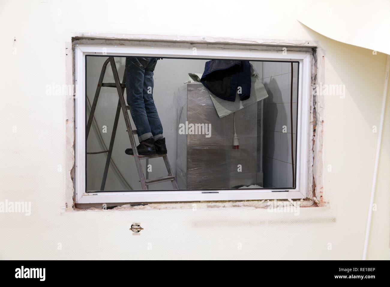 Worker in uniform stands on stepladder in a window opening. Concept ...