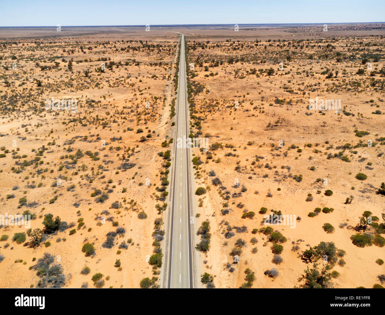 Aerial view of a straight road through a sparse desert landscape under ...