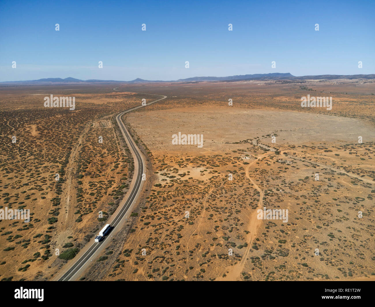 Aerial view of a straight highway cutting through a dry, sparse desert ...