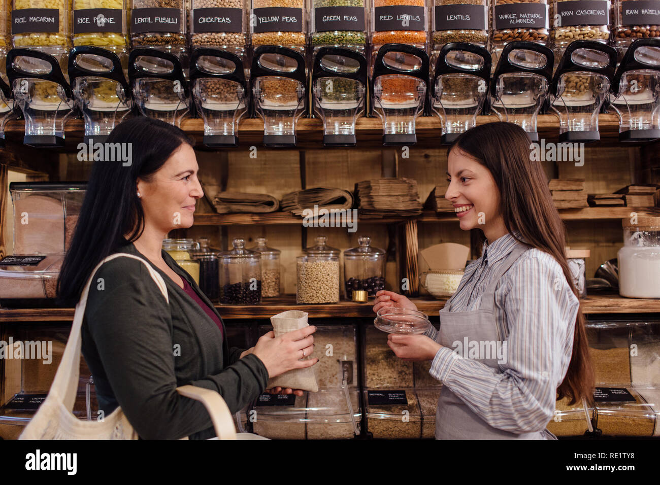 Smiling shop assistant and customer standing against each other in ...