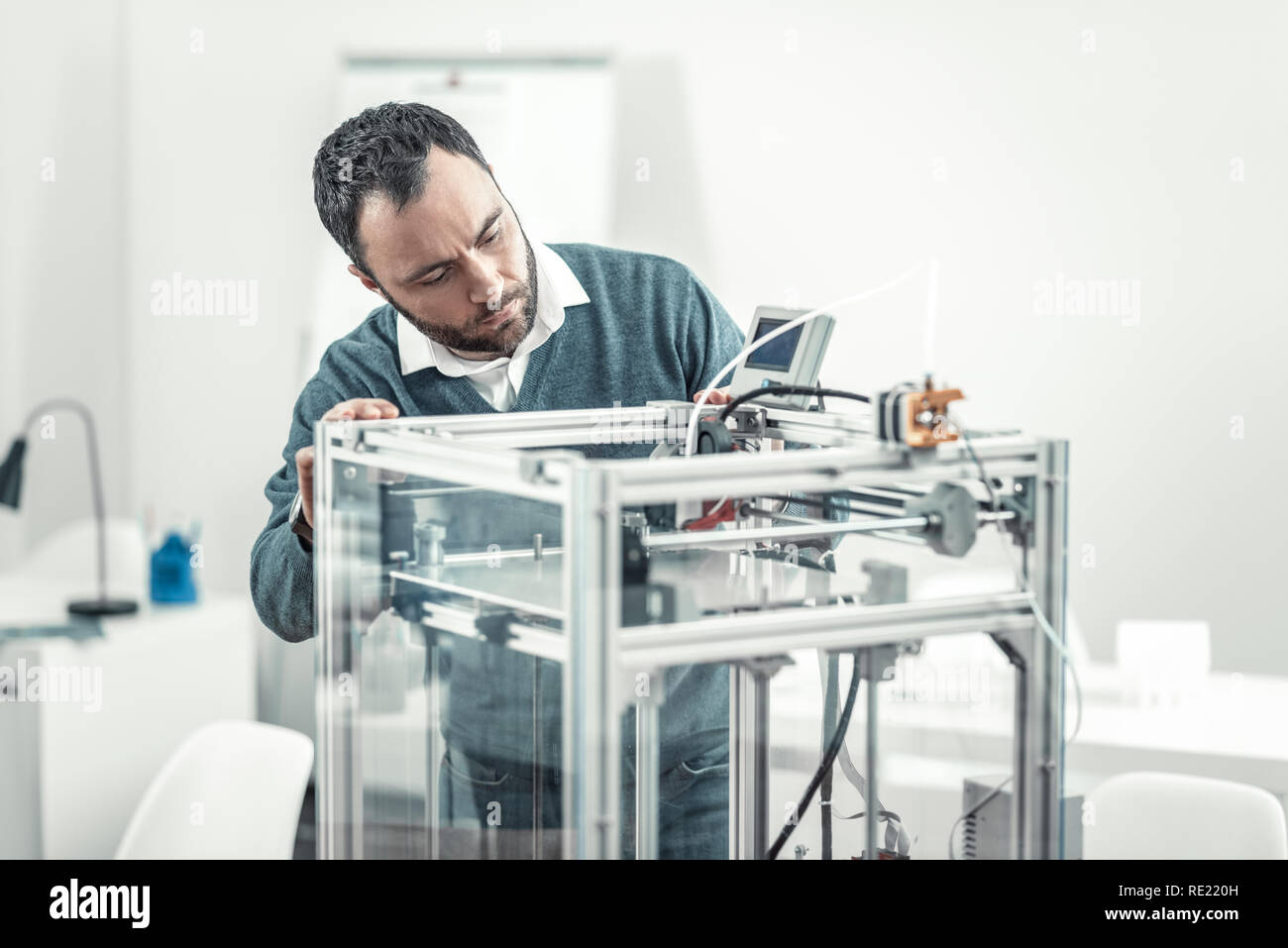 Nice smart man looking at the 3d printer Stock Photo - Alamy