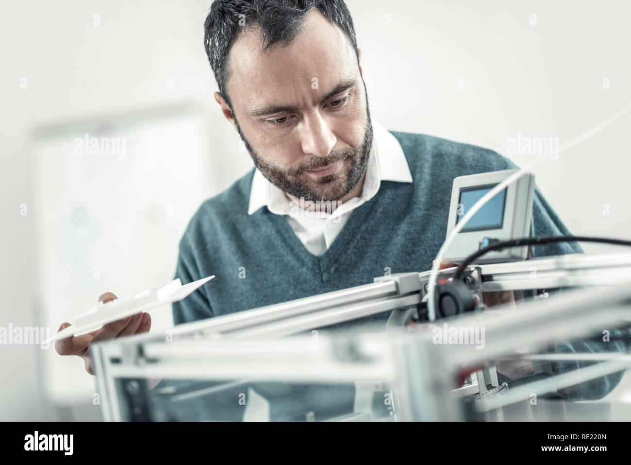 Serious smart technician looking into the 3d printer Stock Photo - Alamy