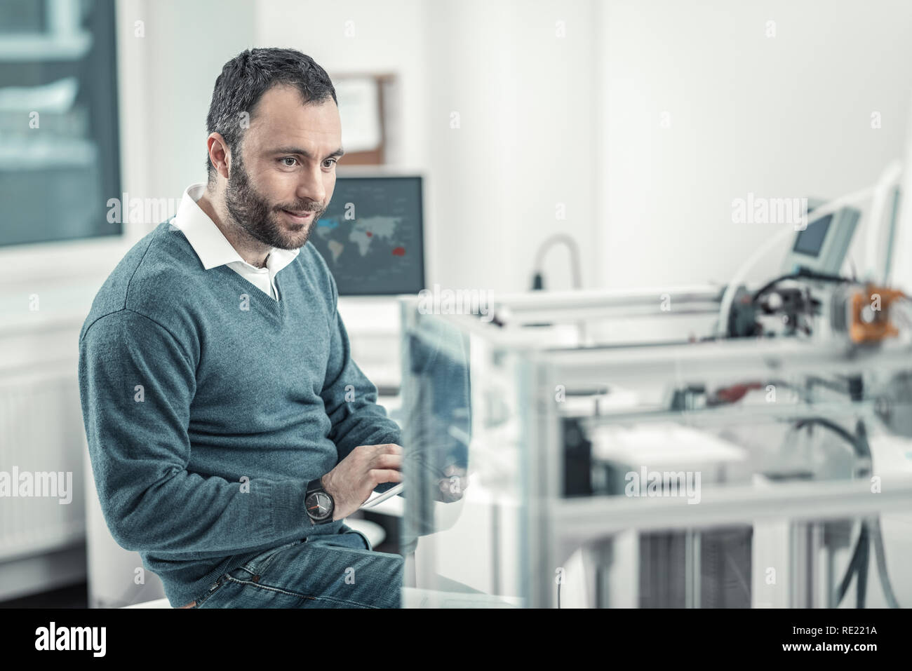 Delighted smart man sitting near the 3d printer Stock Photo - Alamy