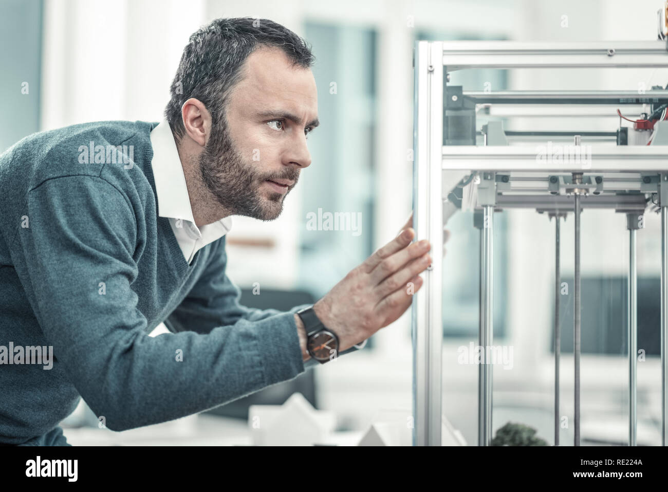 Serious thoughtful man looking at the 3d printer Stock Photo - Alamy