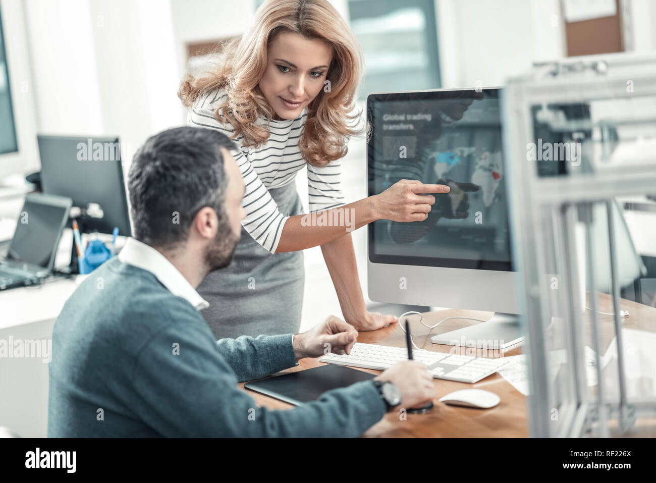 Nice blonde woman pointing at the computer screen Stock Photo - Alamy
