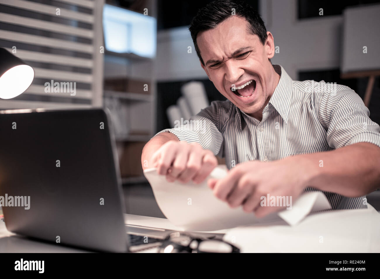 Angry unhappy man tearing down a sheet of paper Stock Photo - Alamy