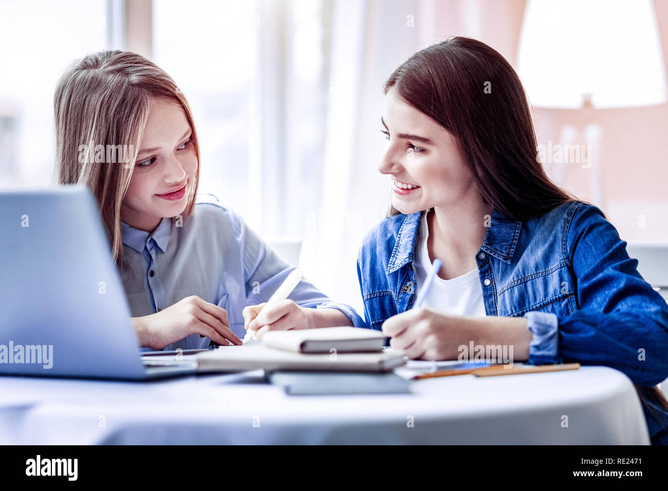 Jolly two girls having first team project Stock Photo - Alamy