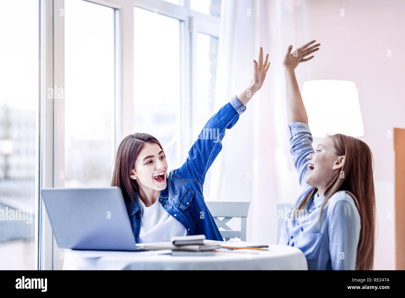 Energetic two girls giving high five after studying Stock Photo - Alamy