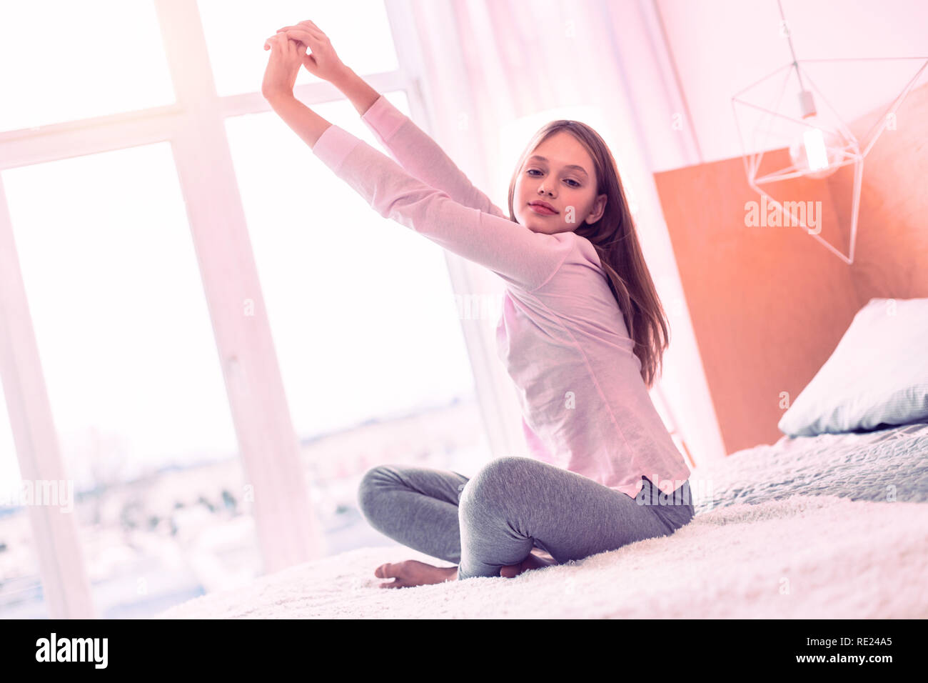 Pleasant girl stretching sitting on her bad Stock Photo - Alamy