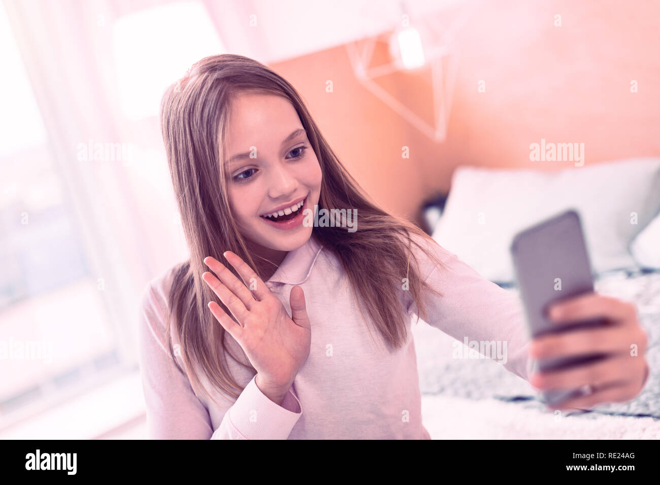 Beautiful girl waving to camera answering to video call Stock Photo - Alamy