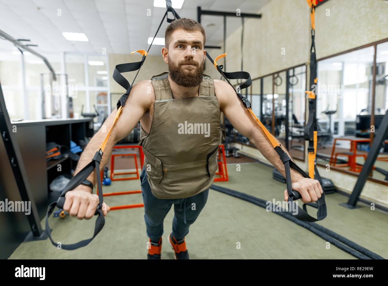Muscular bearded man dressed in military weighted armored vest doing ...