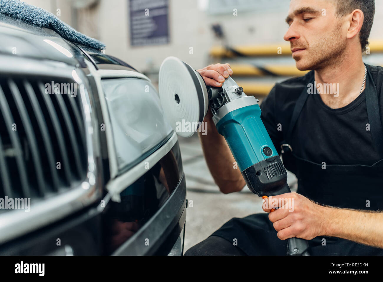 Auto detailing of car headlight on car-wash service. Man works with ...