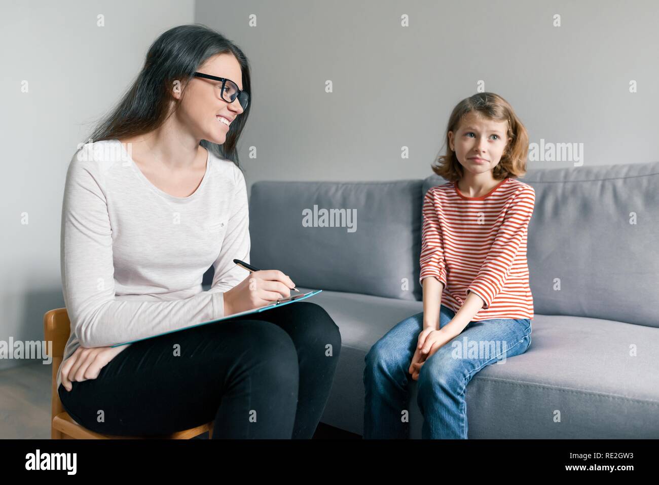Young female psychologist talking with patient child girl in office ...