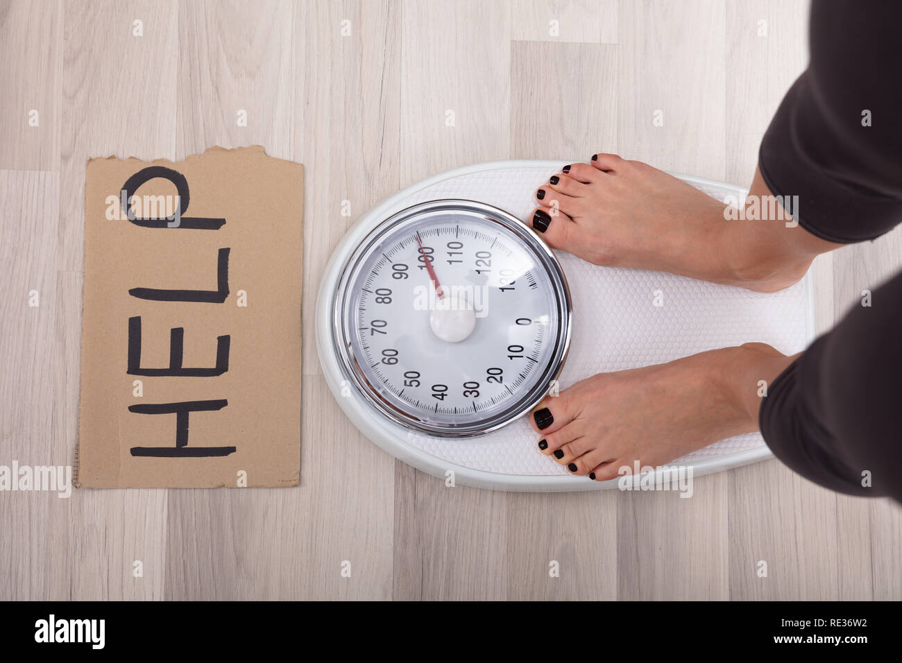 Elevated View Of Help Sign On Cardboard With Woman's Feet On Weighing ...