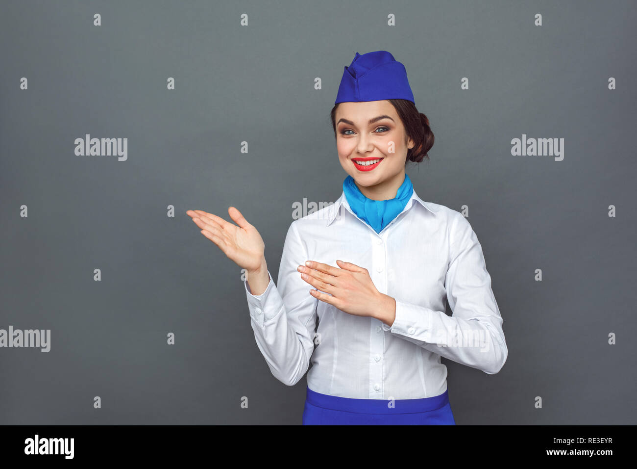Safety Regulations. Stewardess standing isolated on grey showing space ...