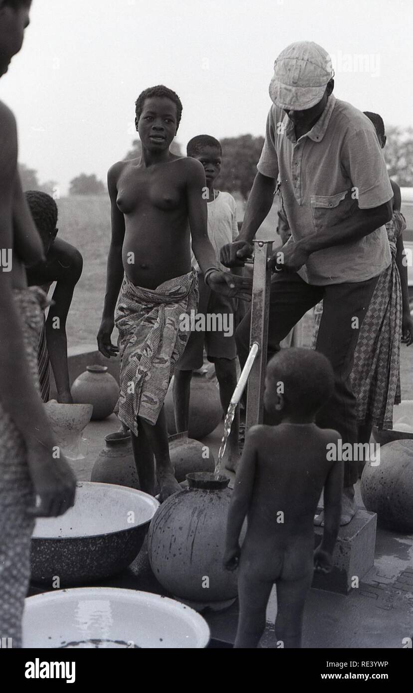PERSON PUMPING WATER FROM A WELL, WHILE OTHERS RETRIEVE Stock Photo - Alamy