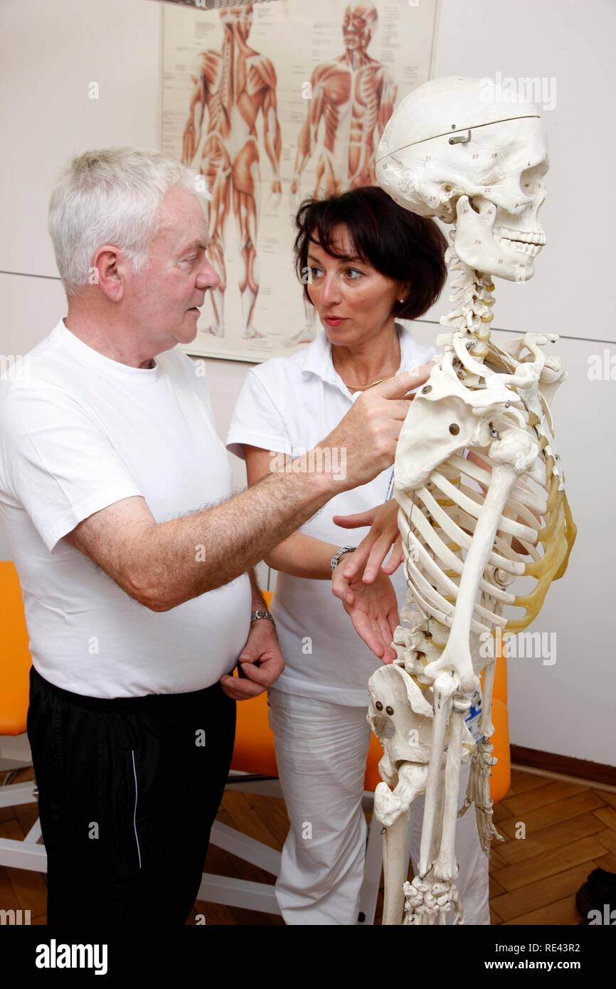 Therapist explaining to a patient on the basis of a skeleton the ...