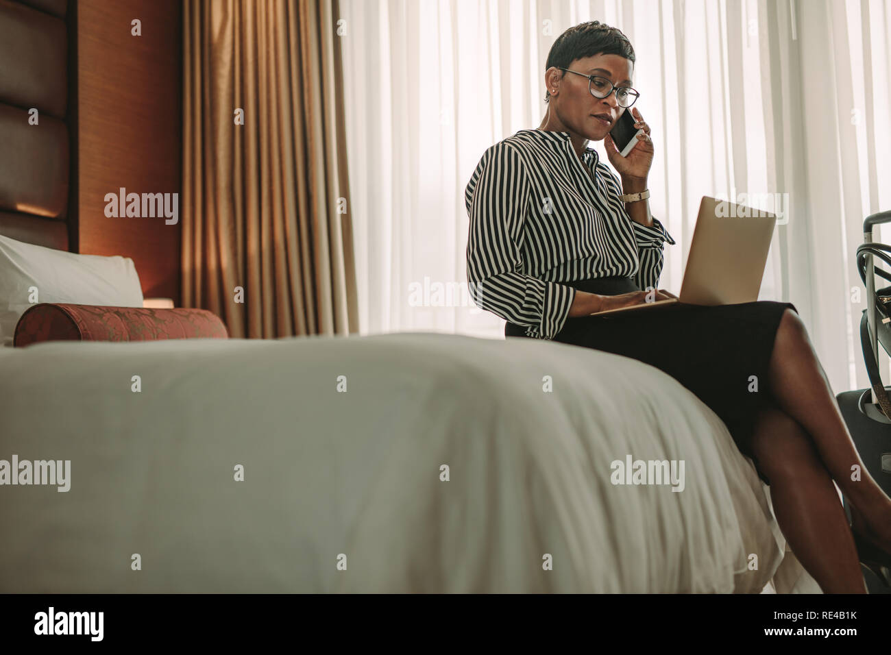 African businesswoman on tour working with laptop computer and mobile ...