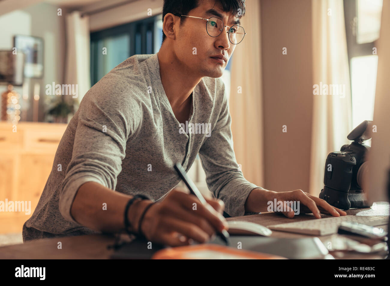 Photographer using a tablet and stylus pen to do photo editing in his ...