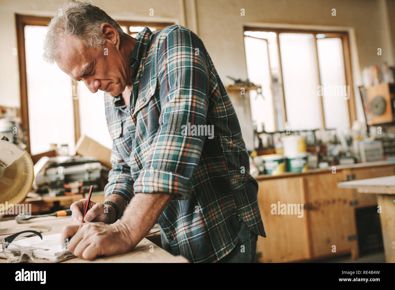 Skilled caucasian male carpenter making drawings on clipboard. Owner of ...