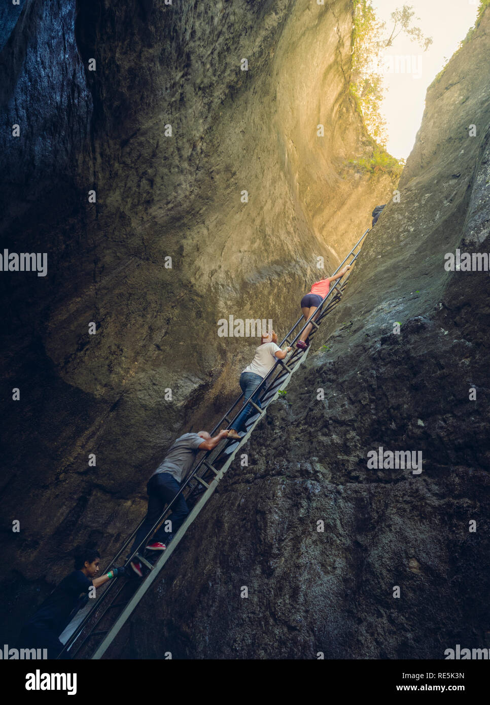 Tourists climb a ladder against the steep rocky walls of the Seven ...
